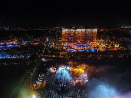 Um hotel com um edifício grande e uma área de piscina iluminada.