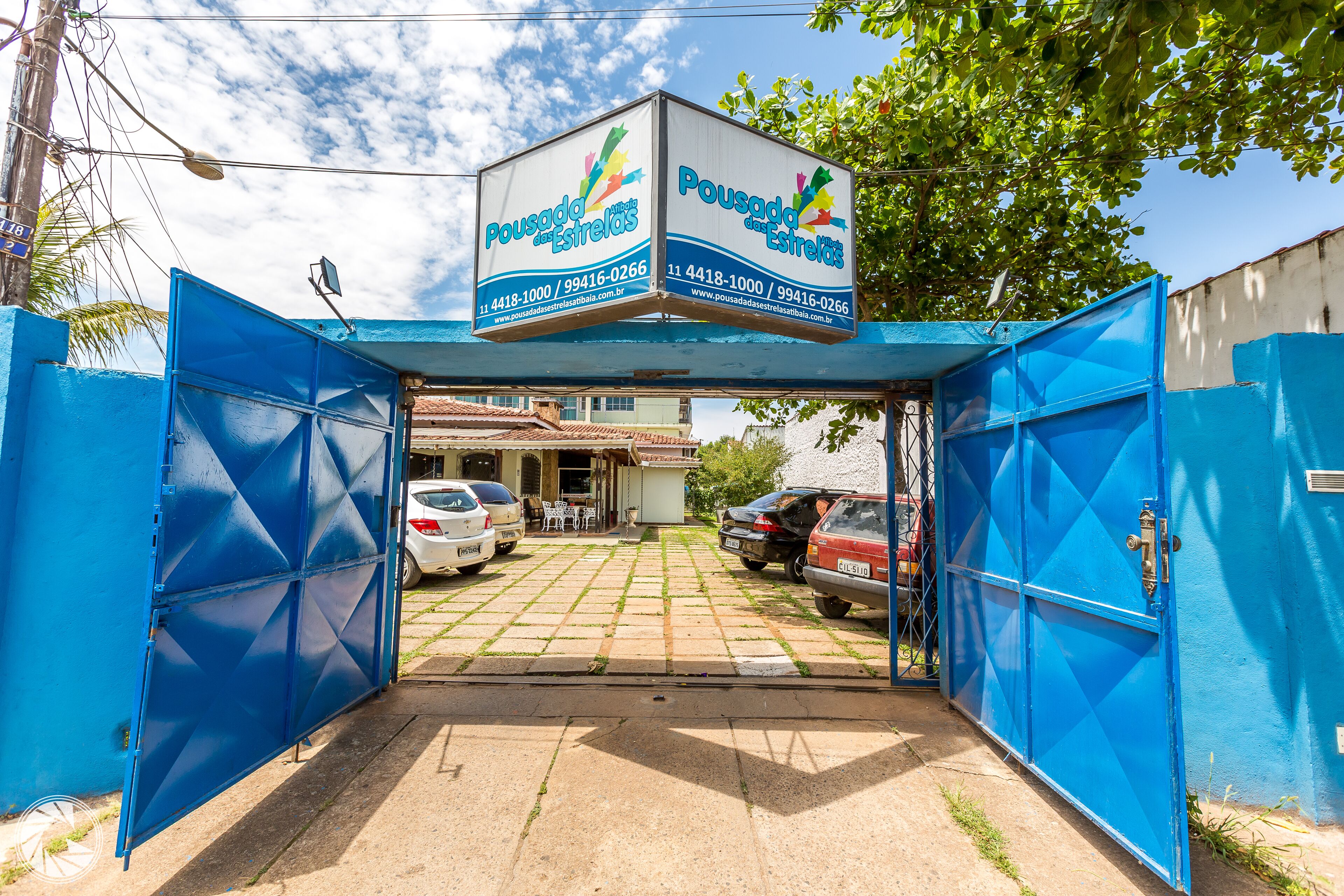 Uma entrada com portão e placa indicando Pousada dos Estrelets, exibindo um número de contato e site.