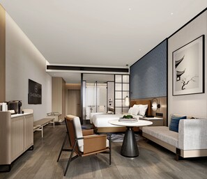 Quarto de hotel moderno com cama, sofá, área de refeições e banheiro.