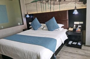 Quarto de hotel com cama, mesa de cabeceira e telefone fixado na parede.