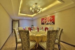 Uma sala de conferências com mesa redonda, cadeiras de padrão floral e um lustre.