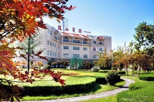 Um hotel com um pátio central, um caminho de pedras e um jardim bem cuidado.