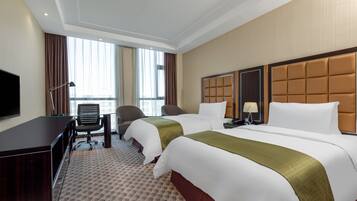 Quarto de hotel com duas camas, uma escrivaninha, uma cadeira e uma televisão.