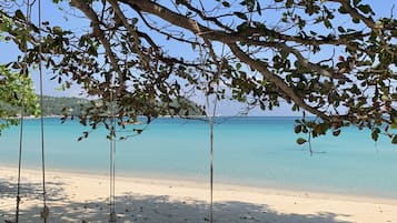 Na praia, areia branca, espreguiçadeiras, guarda-sóis