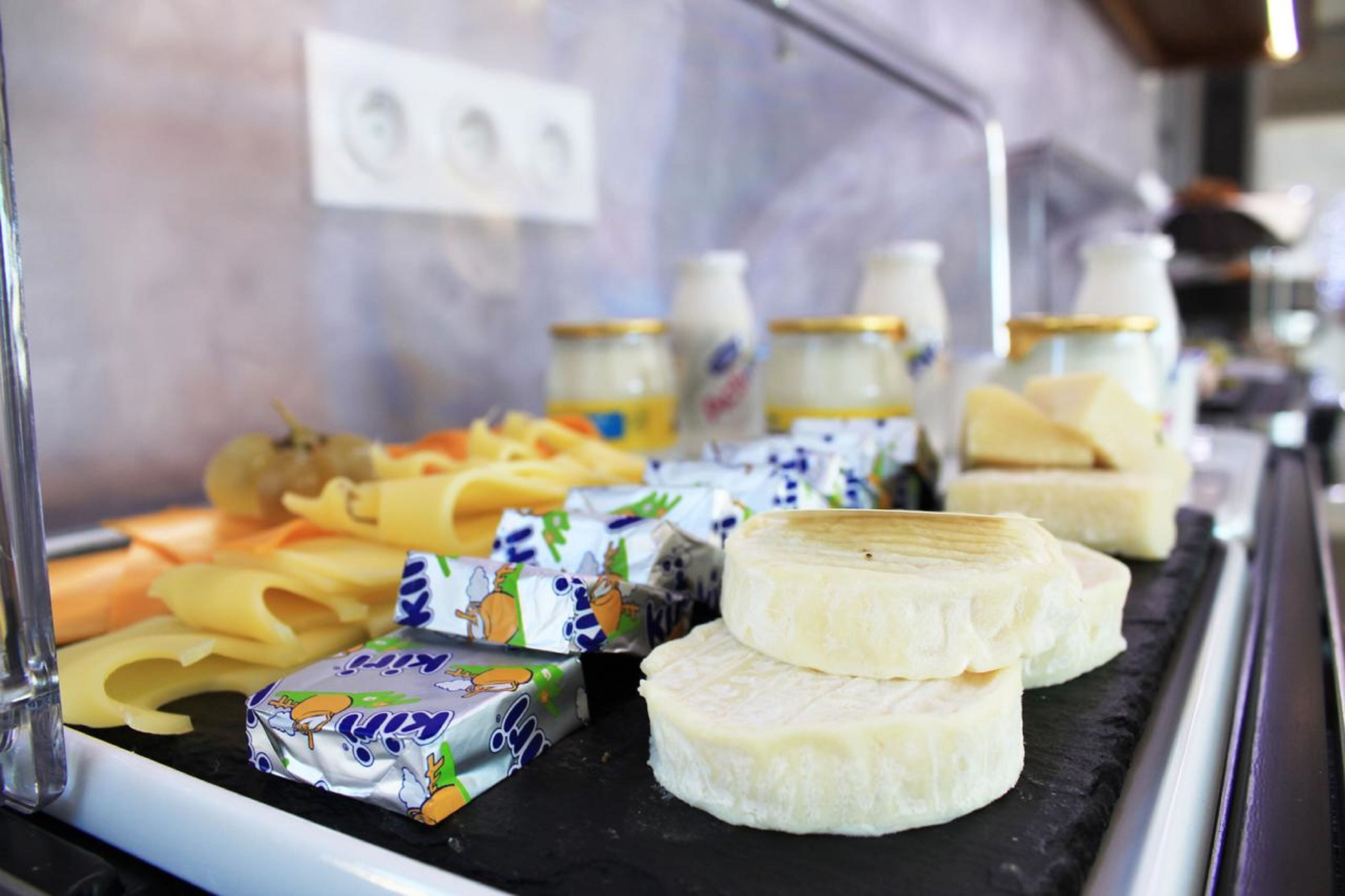 Exposição de queijos e petiscos, com diversos tipos de queijo e lanches embalados.