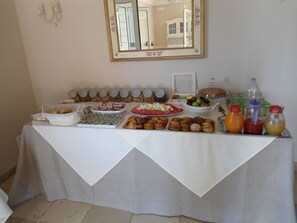 Uma mesa de buffet com diversos alimentos e bebidas.