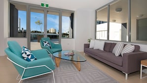 Uma sala de estar moderna com poltronas verde-água, uma mesa de centro de vidro e um sofá cinza.