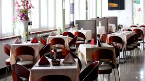 Restaurante com mesas e cadeiras dispostas para refeições.