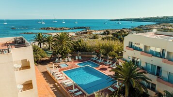 Piscina no terraço com espreguiçadeiras e vista para o mar.