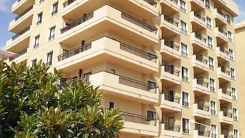 Um edifício residencial com vários andares, varandas, um andar térreo pavimentado e uma placa com o nome 'Ronda 4'.
