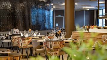 Um restaurante com mesas redondas, cadeiras e um espaço de bar.
