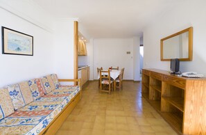 Uma sala de estar acolhedora com um sofá, uma mesa de jantar e um armário de madeira.