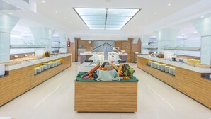 Um saguão de hotel moderno com uma recepção central, guarda-corpos de vidro e um grande skylight.