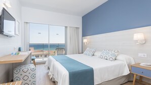 Quarto de hotel moderno com uma cama grande, uma mesa de escritório e vista para o mar.