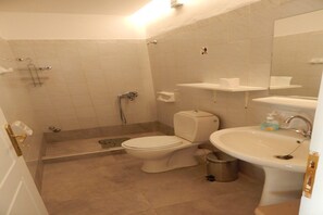 Casa de banho com sanita, lavatório e chuveiro.