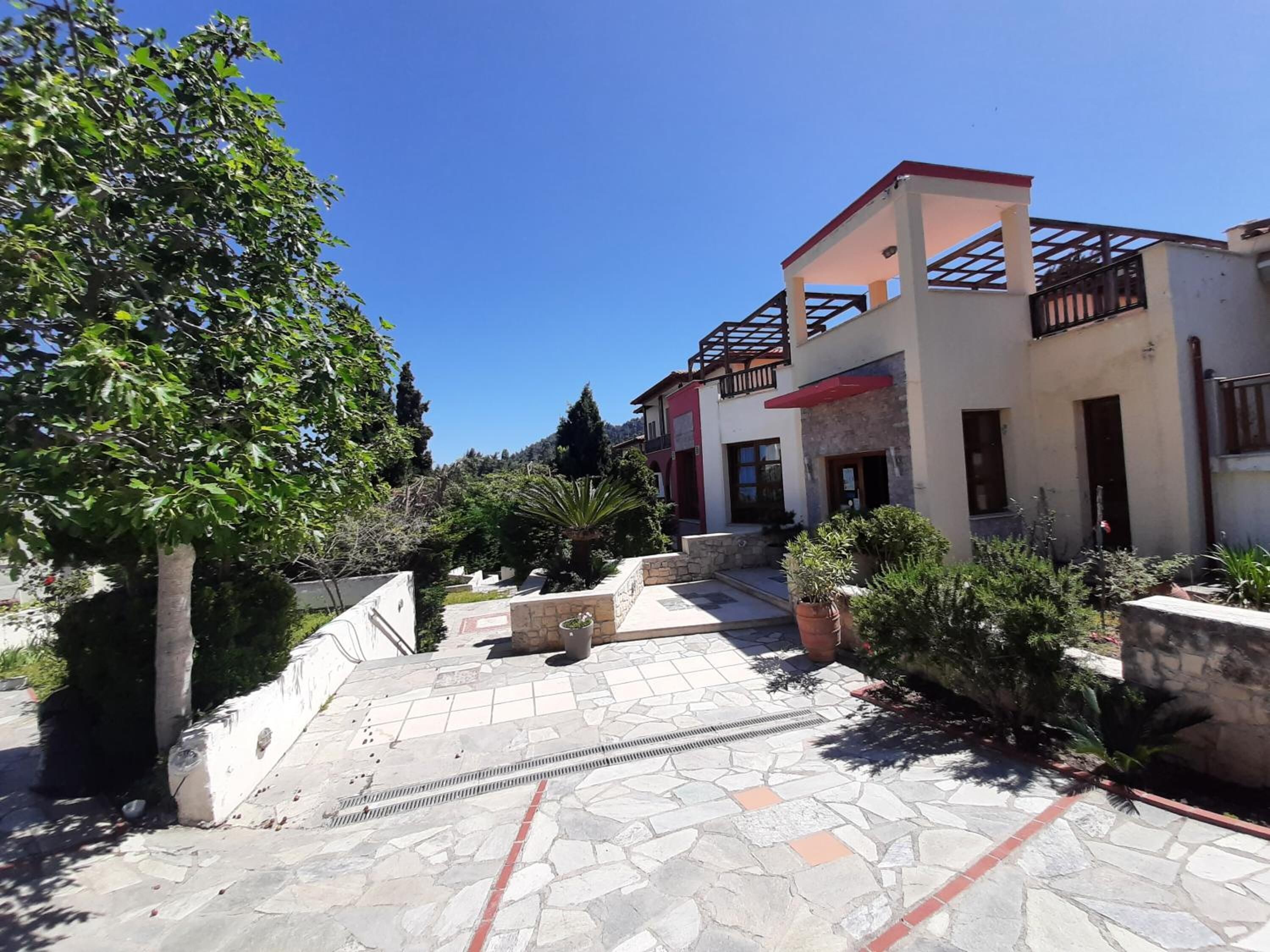 Uma casa de dois andares com um alpendre de pedra e um jardim.
