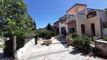 Uma casa de dois andares com um alpendre de pedra e um jardim.