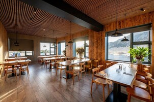 Restaurante com interiores em madeira, grandes janelas e vista para o exterior.