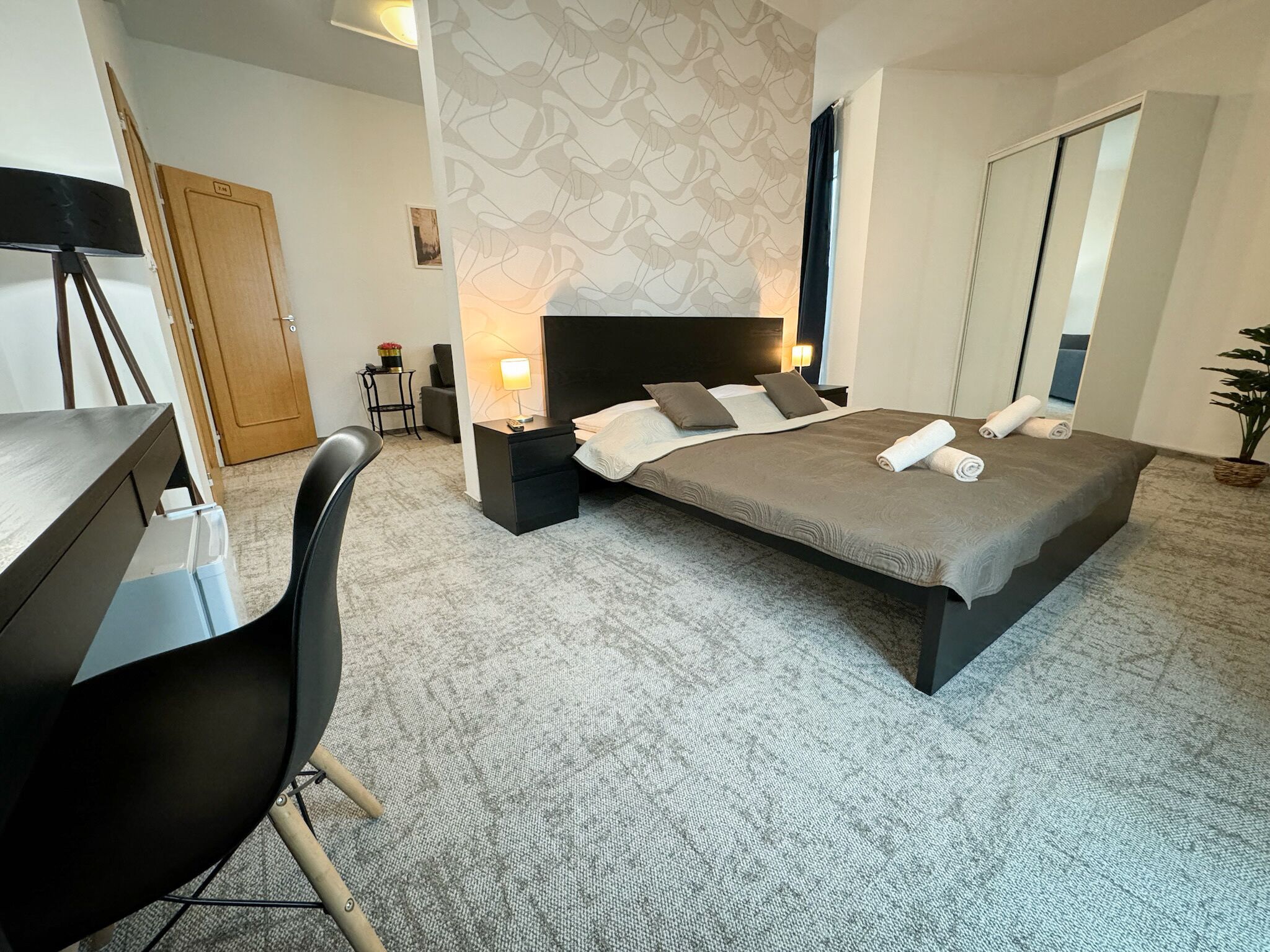 Quarto de hotel moderno com uma cama grande, uma escrivaninha e uma cadeira.