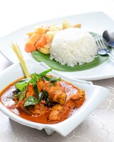 Prato de curry com legumes e acompanhamento de arroz branco, servido em folha de bananeira.