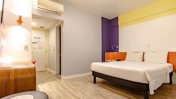 Quarto de hotel com cama, secretária e ar condicionado.
