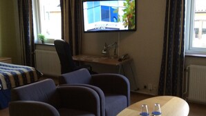 Quarto de hotel com televisão, dois sofás, mesa de centro e cama.