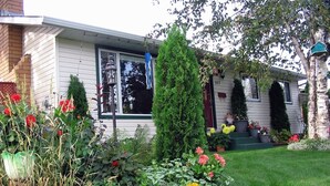 Uma casa com um jardim da frente, um pequeno jardim com várias plantas e flores, e uma caixa de correio.