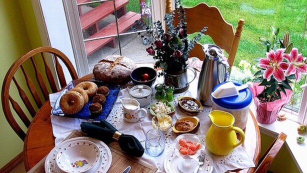 Uma mesa de café da manhã posta com pratos, xícaras e diversas opções de comida.