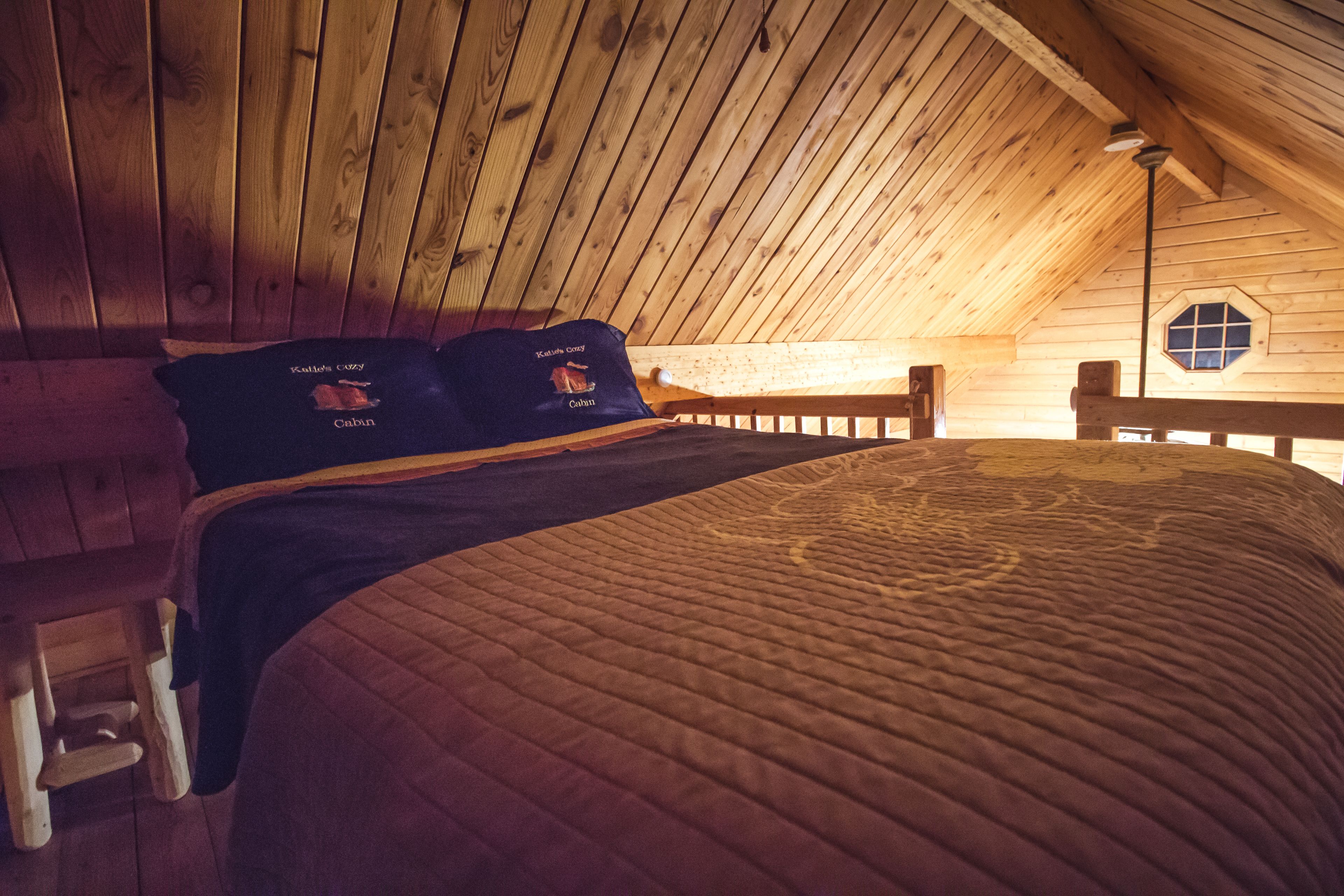 Um quarto de cabana de madeira aconchegante, com cama, almofadas e janela.