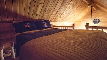 Um quarto de cabana de madeira aconchegante, com cama, almofadas e janela.