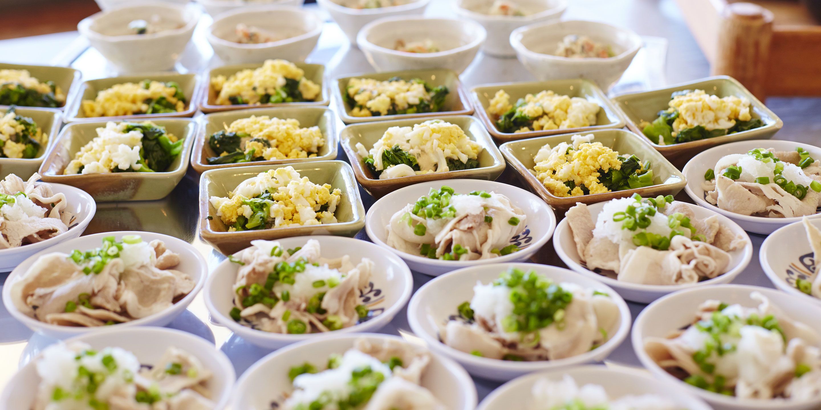 Diversos pratos dispostos em tigelas e pratos, provavelmente um buffet ou exposição de comida.