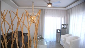 Uma sala de estar moderna com um sofá, uma poltrona branca, uma mesa de centro e uma estrutura decorativa de madeira.