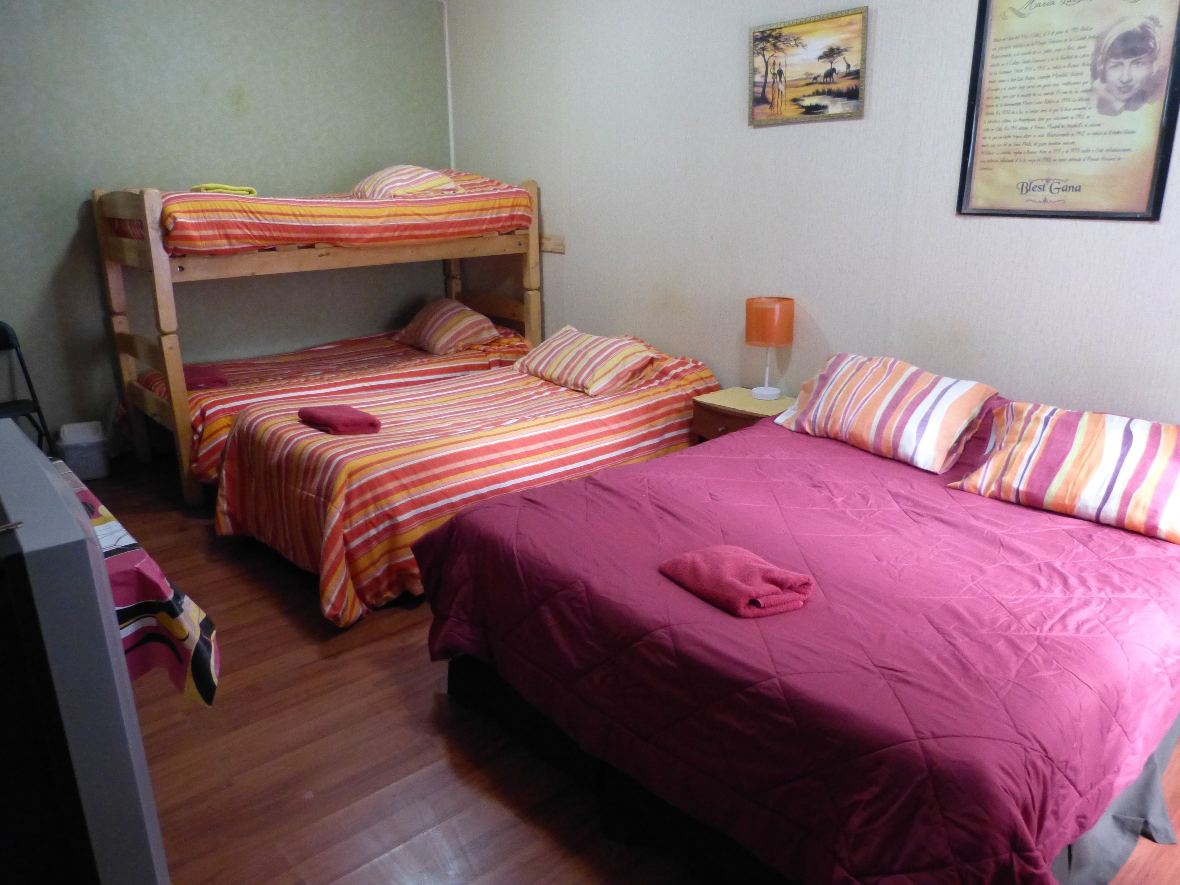 Quarto de dormitório com beliches, uma escrivaninha e uma mesa de cabeceira com abajur.