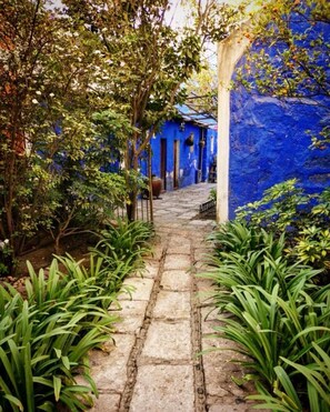 Uma trilha de pedras que leva a um edifício com paredes azuis e telhado de telhas.