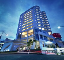 Um hotel moderno com vários andares, grandes janelas e uma entrada destacada com degraus.