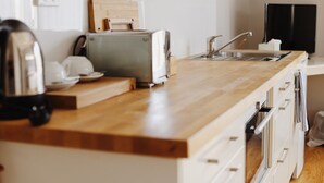 Uma cozinha moderna com bancada de madeira, torradeira, chaleira e pia.