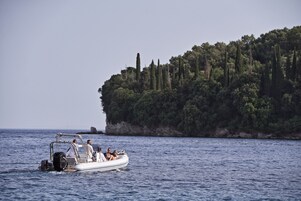 Um barco com passageiros em um mar calmo, cercado por uma ilha coberta de floresta.