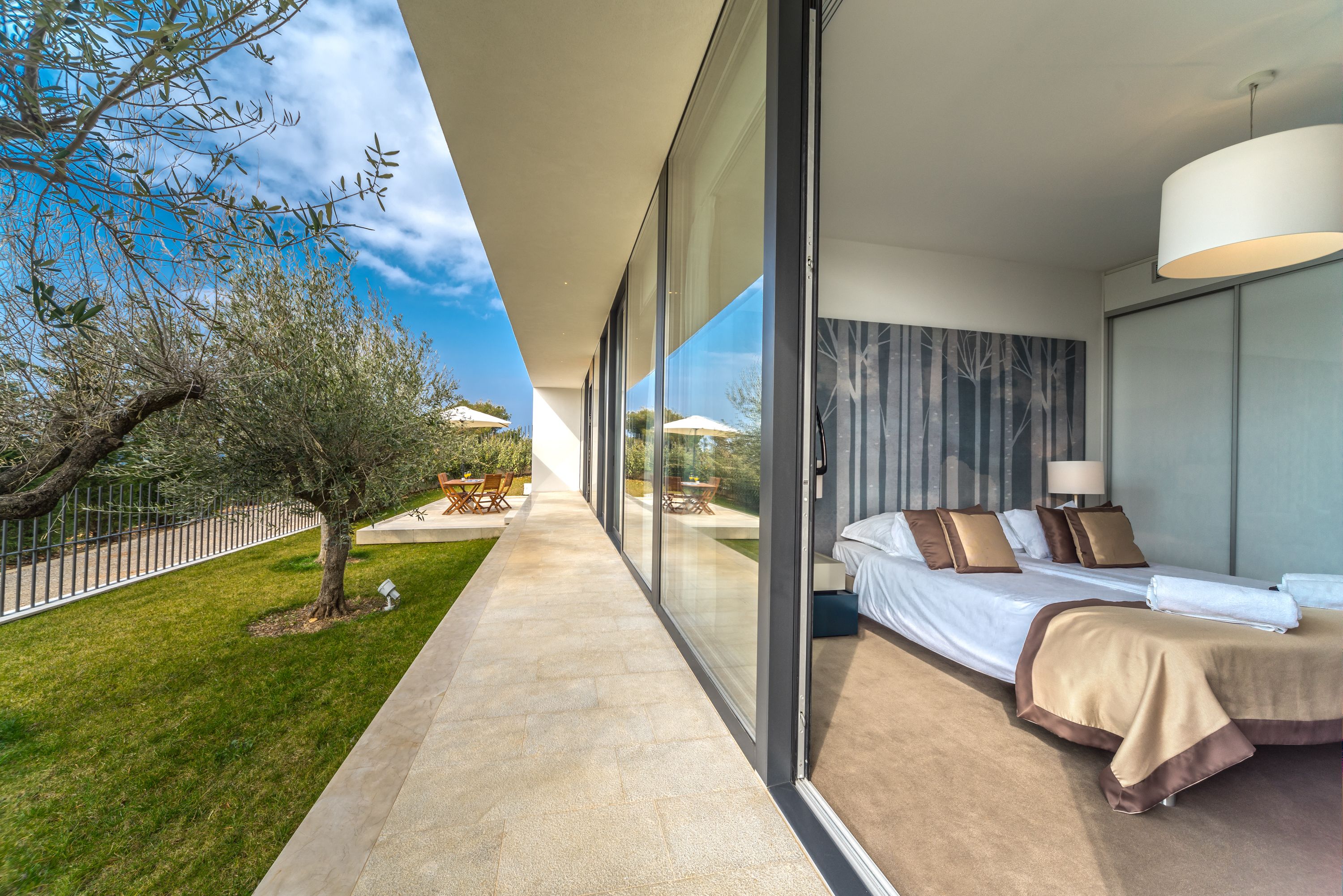 Quarto moderno com uma cama grande, vista para o jardim e uma parede de vidro.