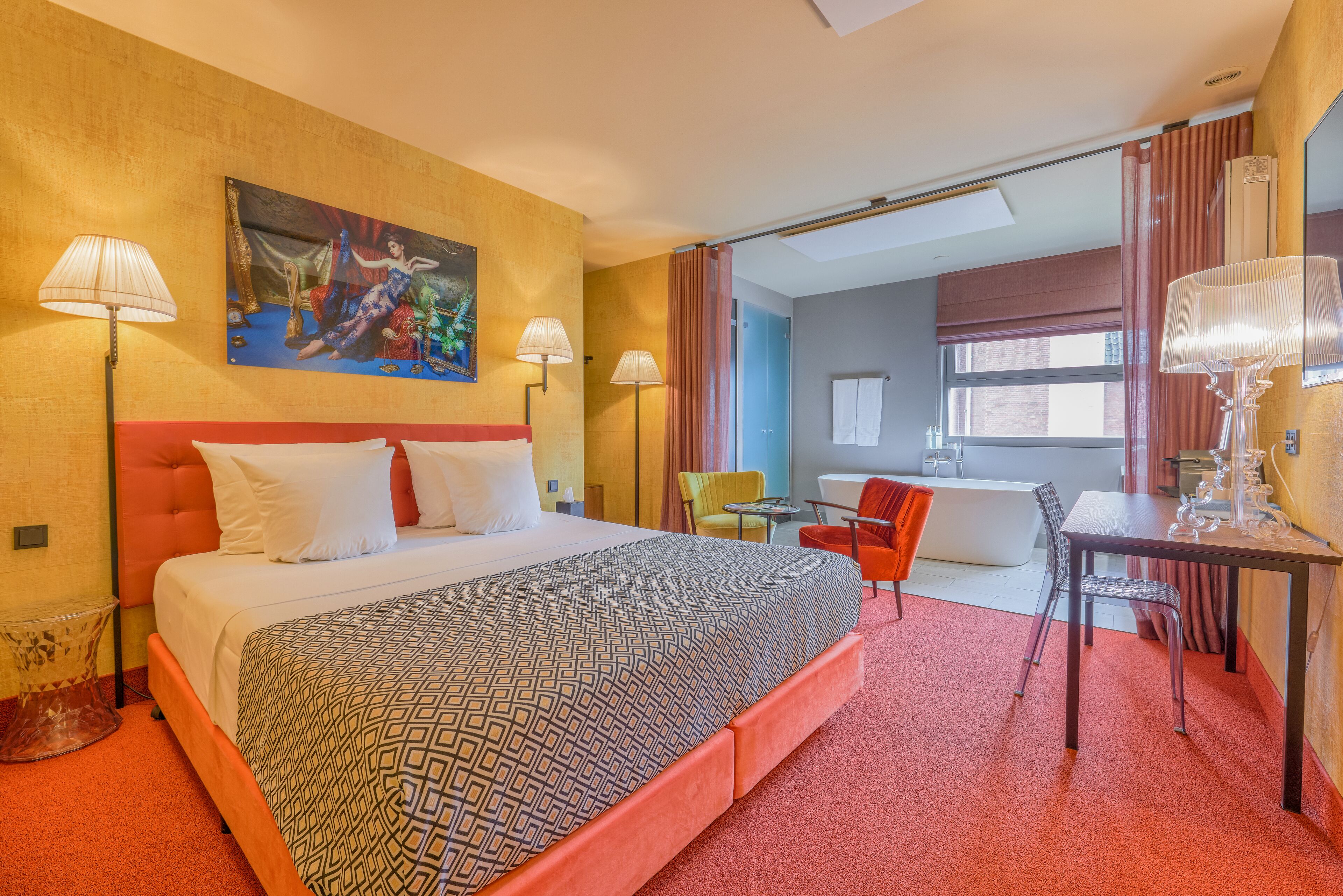 Quarto de hotel com uma cama grande, uma escrivaninha, uma cadeira, uma banheira e um quadro na parede.