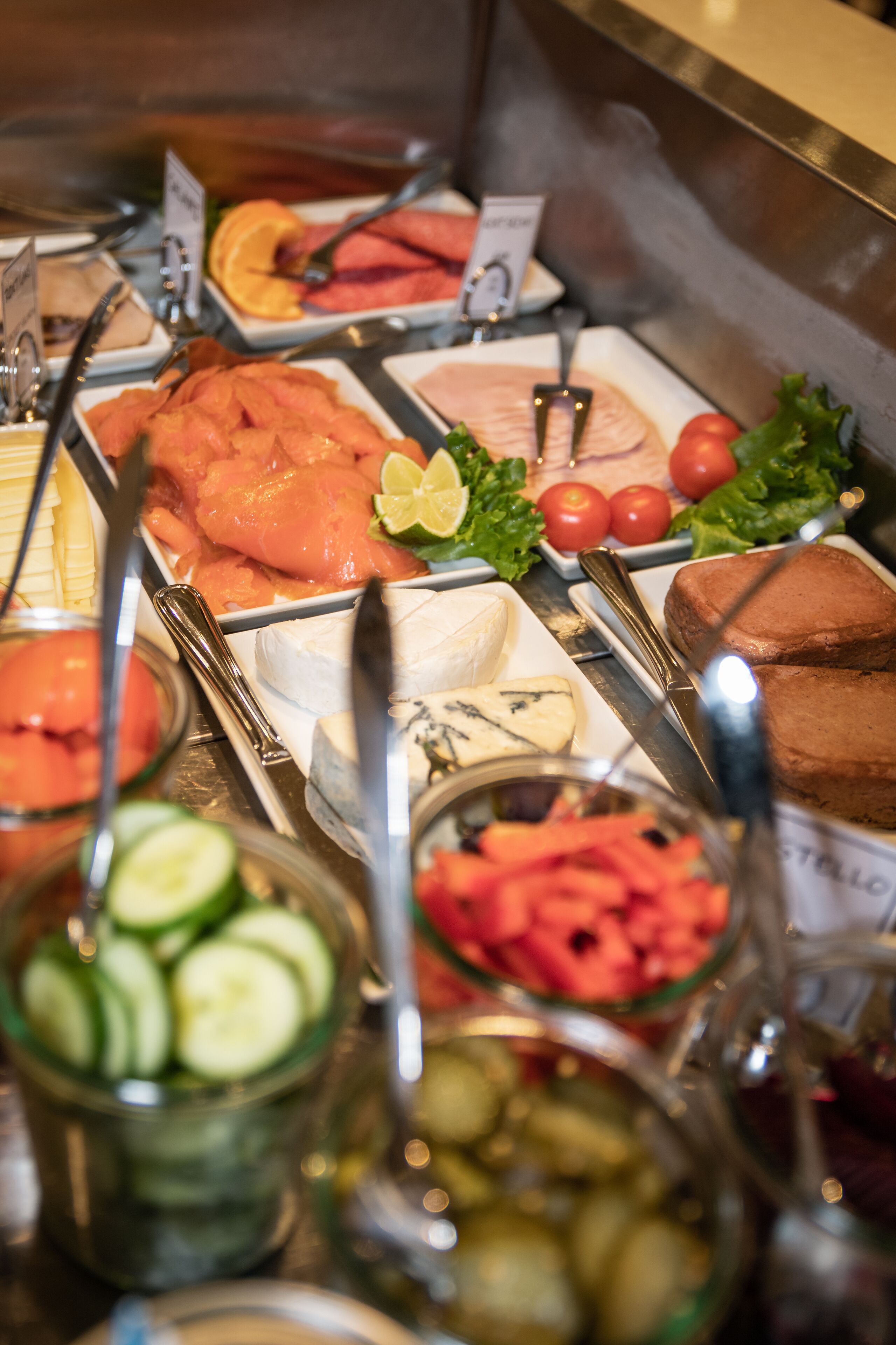 Buffet com diversos alimentos, incluindo carnes, queijos e vegetais.