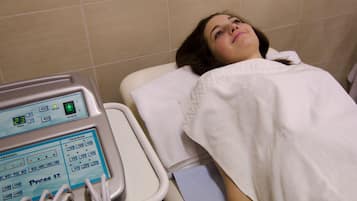 Paciente deitado em uma cama de hospital com um monitor médico exibindo hora e configurações do programa.