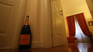 Uma garrafa de vinho sobre um chão de madeira em um quarto com porta e cortinas.