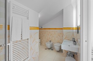 Casa de banho moderna com lavatório branco, bidé e porta-toalhas.