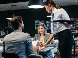 Reunião de negócios num escritório moderno, com uma mesa, cadeiras e iluminação suspensa.