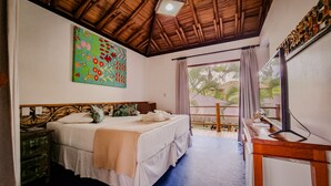 Quarto com cama, escrivaninha, um quadro e vista para o exterior.
