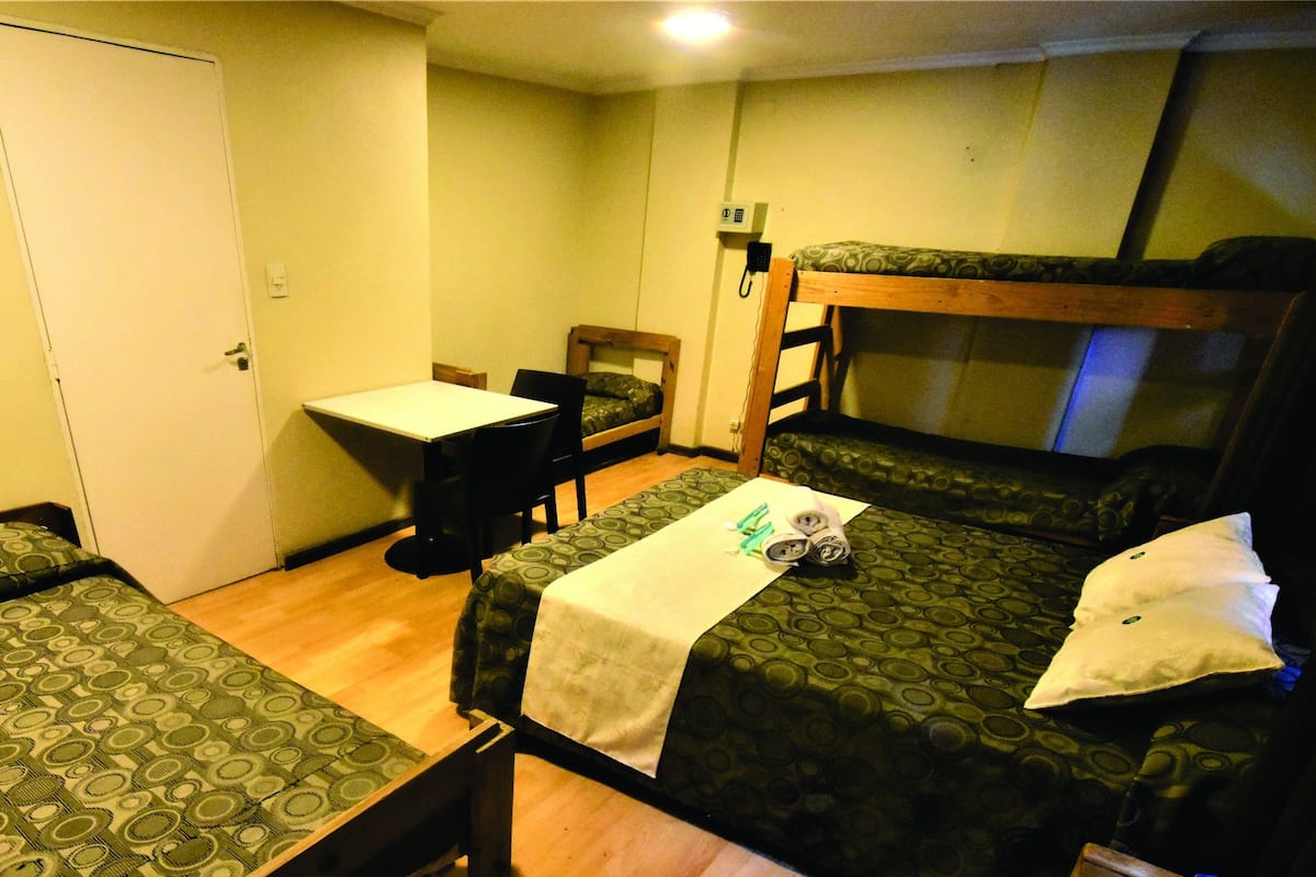 Quarto com beliches, uma mesinha e uma cadeira.