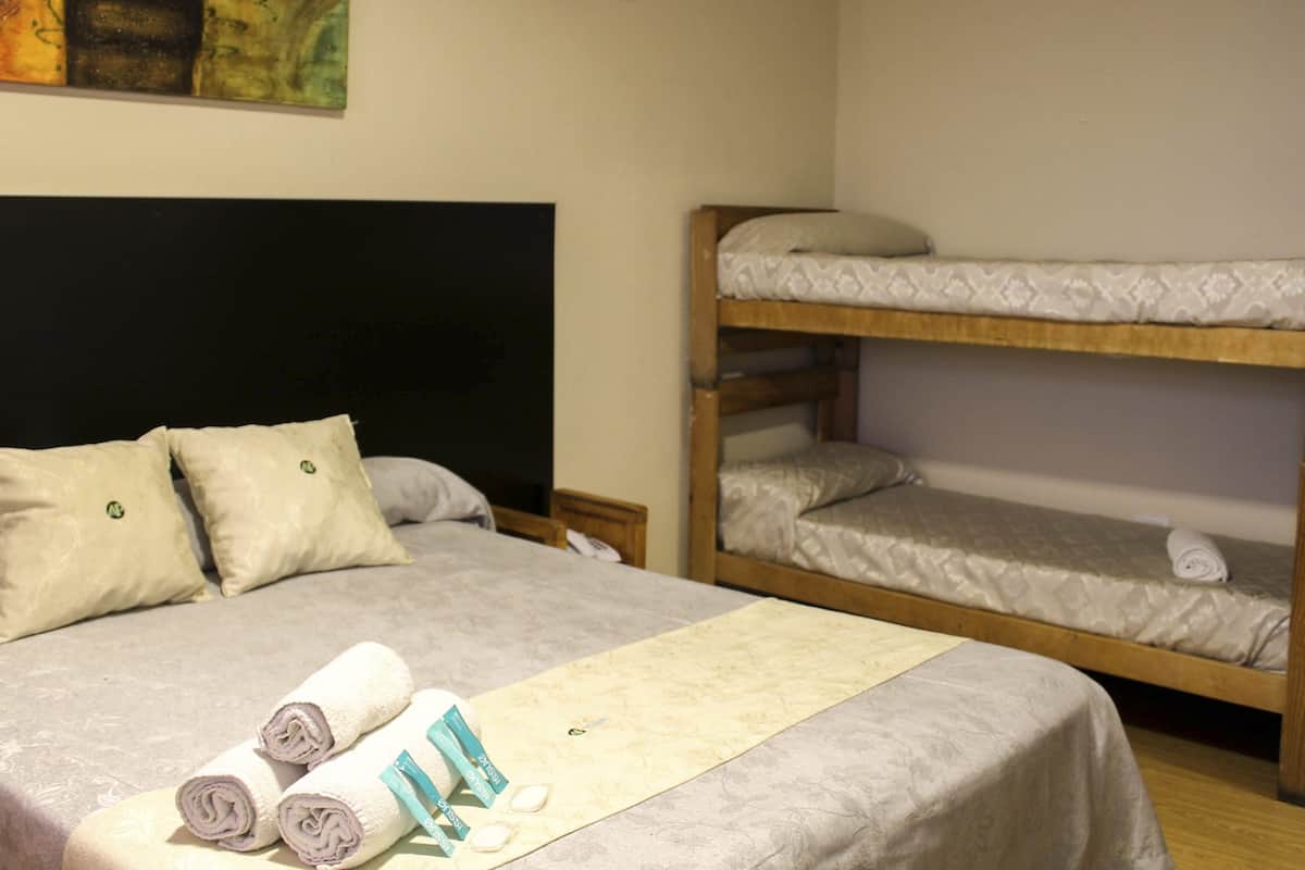 Quarto com uma cama de solteiro, duas almofadas, uma toalha enrolada e uma cama beliche.