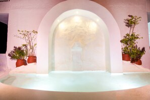 Um quarto com parede branca, uma grande porta em arco e duas plantas em vasos de cada lado.
