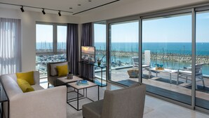 Sala de estar moderna com uma janela ampla com vista para uma marina e o mar.