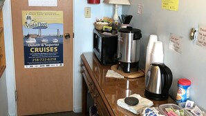 Uma cozinha compacta com bancada de madeira, cafeteira e diversos utensílios.